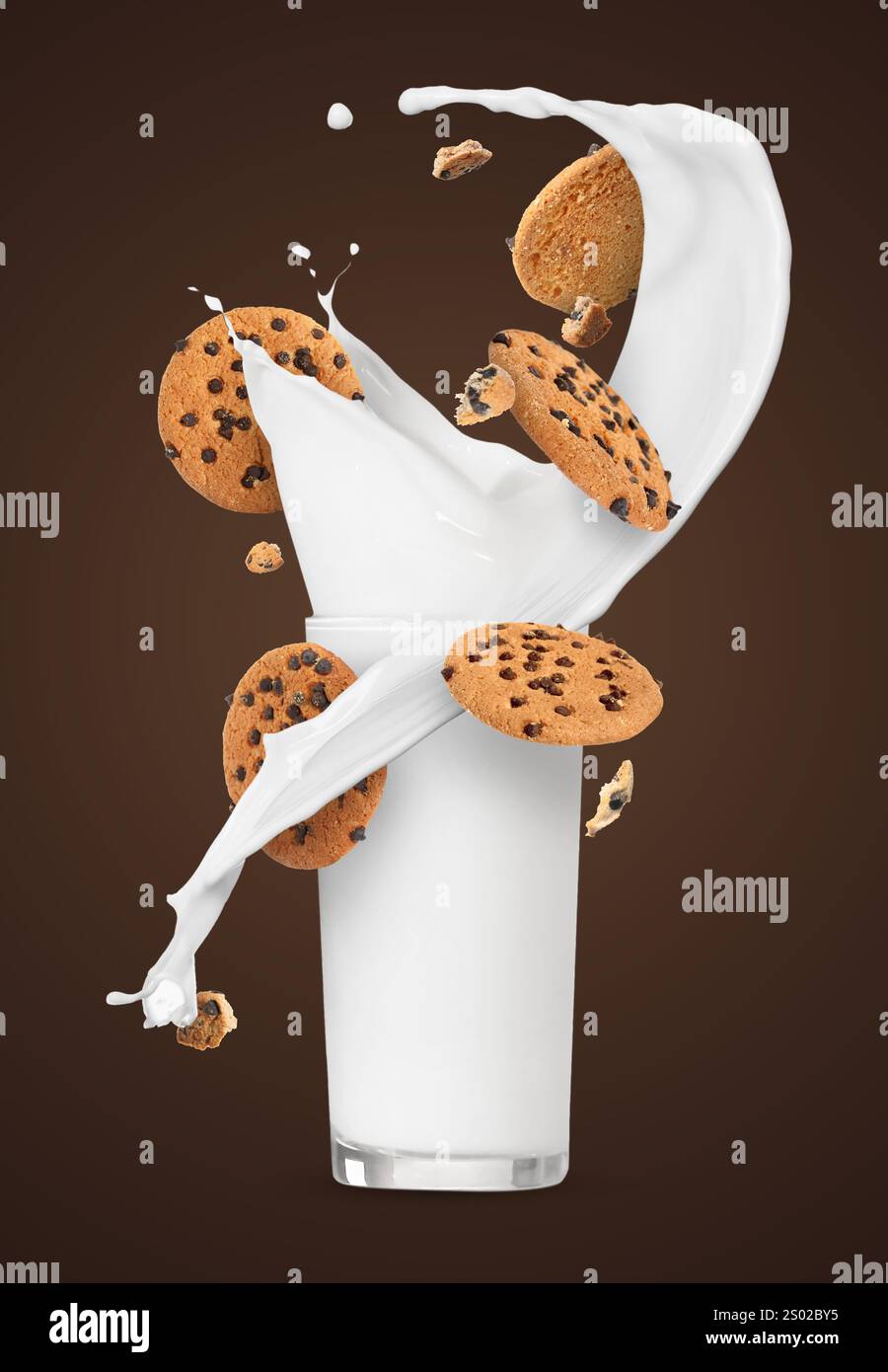 Chocolate chip cookies falling and glass with splashing milk on brown ...