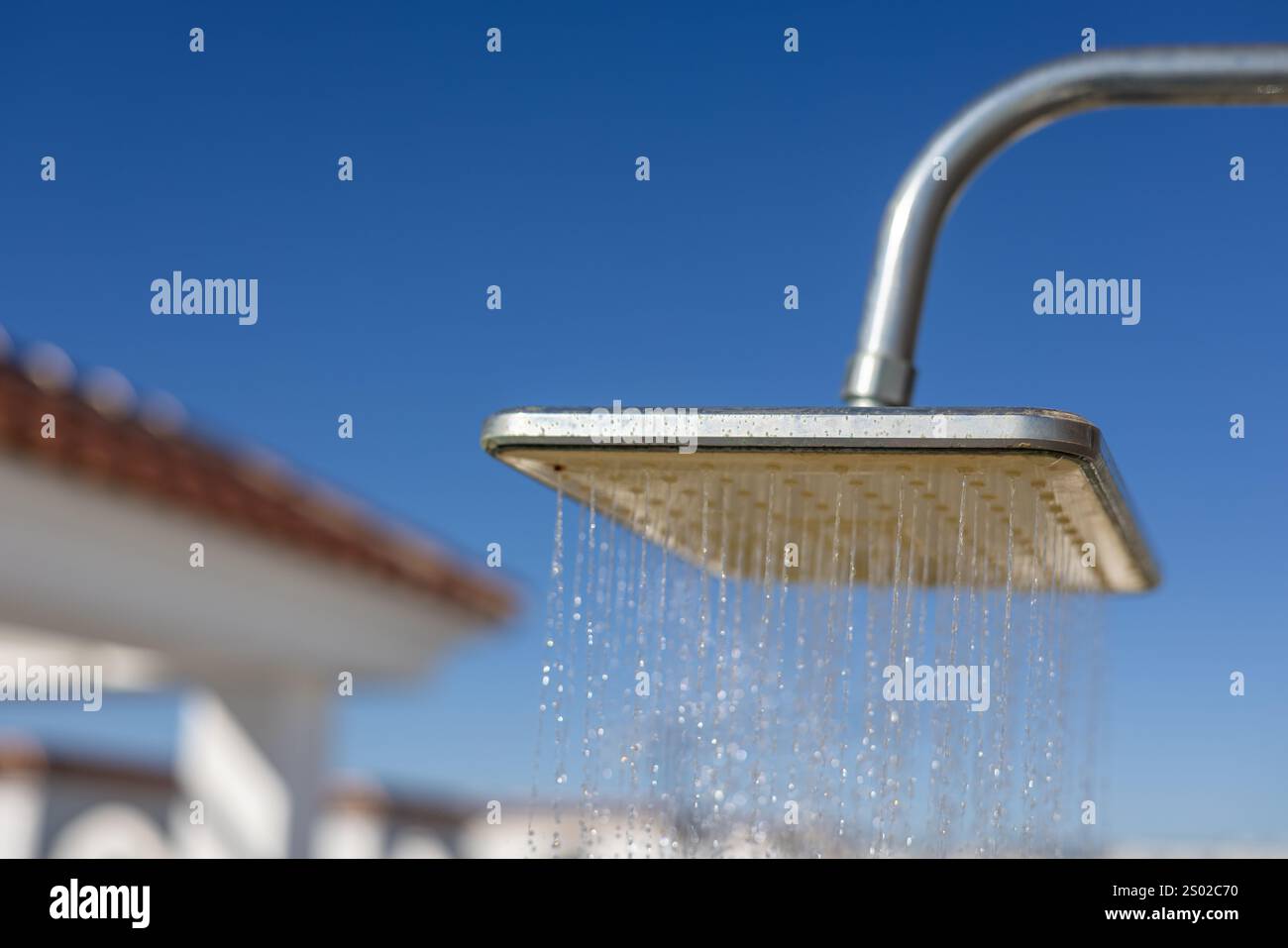 Close-up of a square outdoor shower head with water droplets falling ...