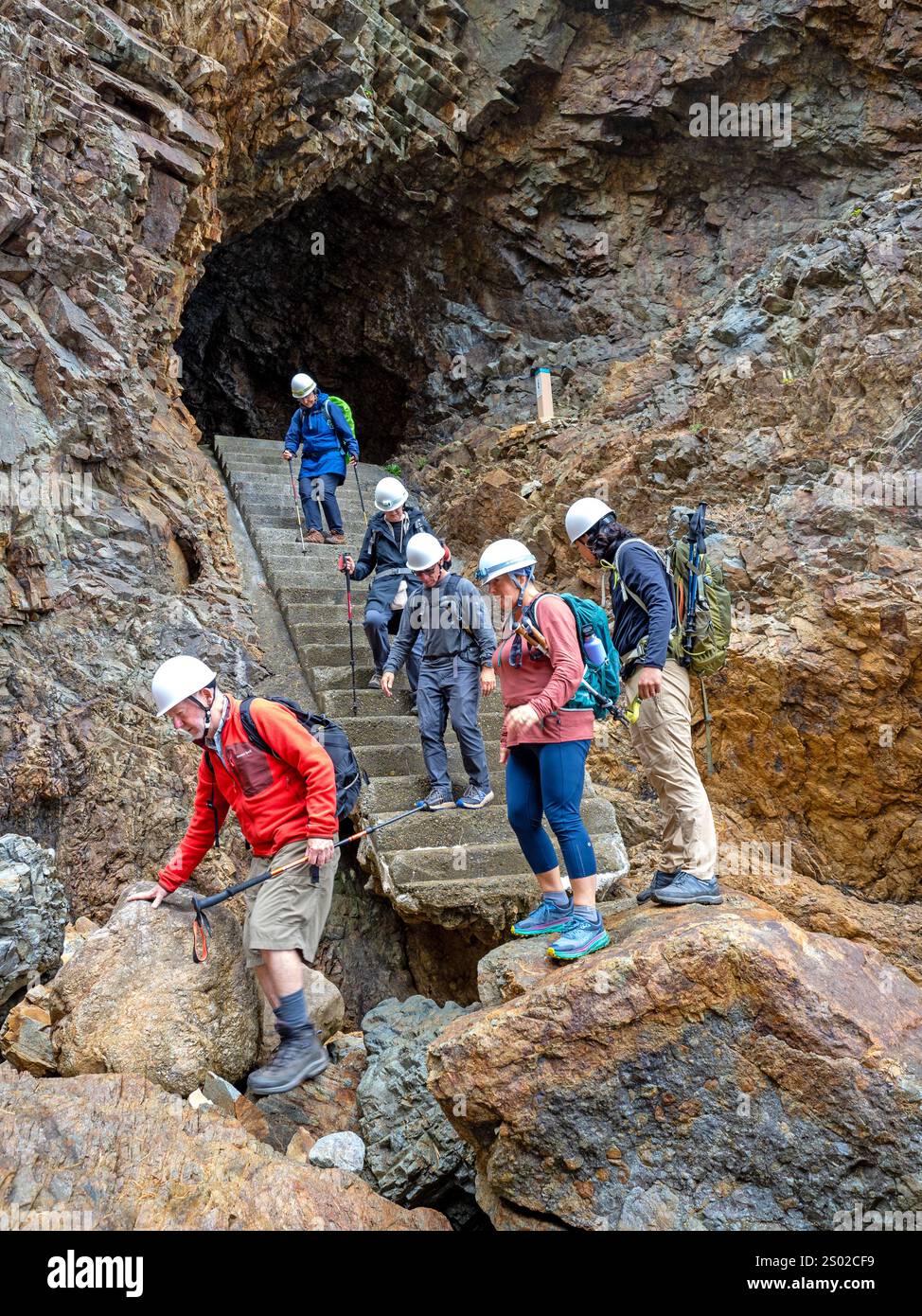 Hikers passing through a tunnel in the Kitayamazaki cliffs along the ...