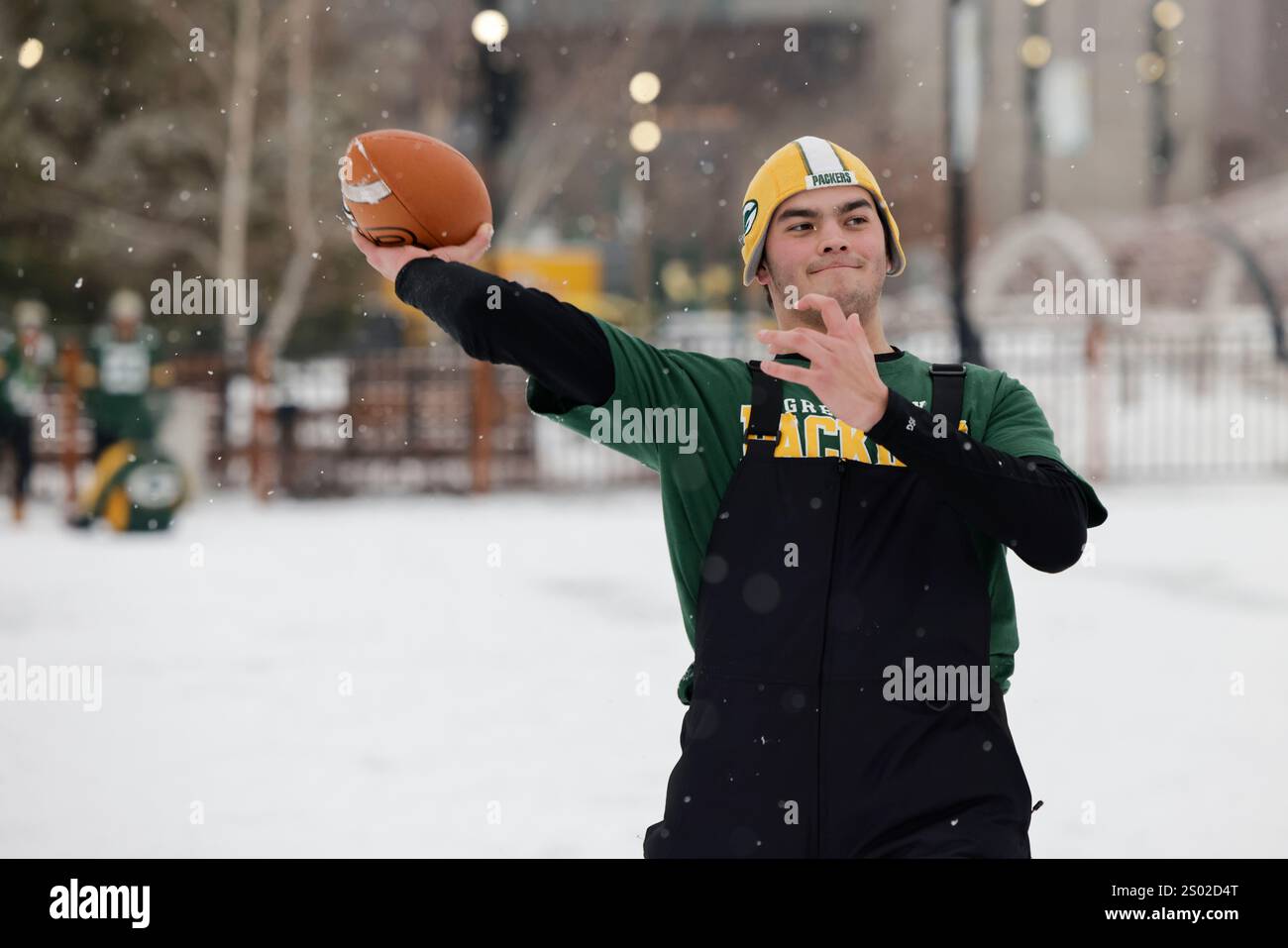 Green Bay Packers fam Sam Mlagan throws a football in the snow outside ...