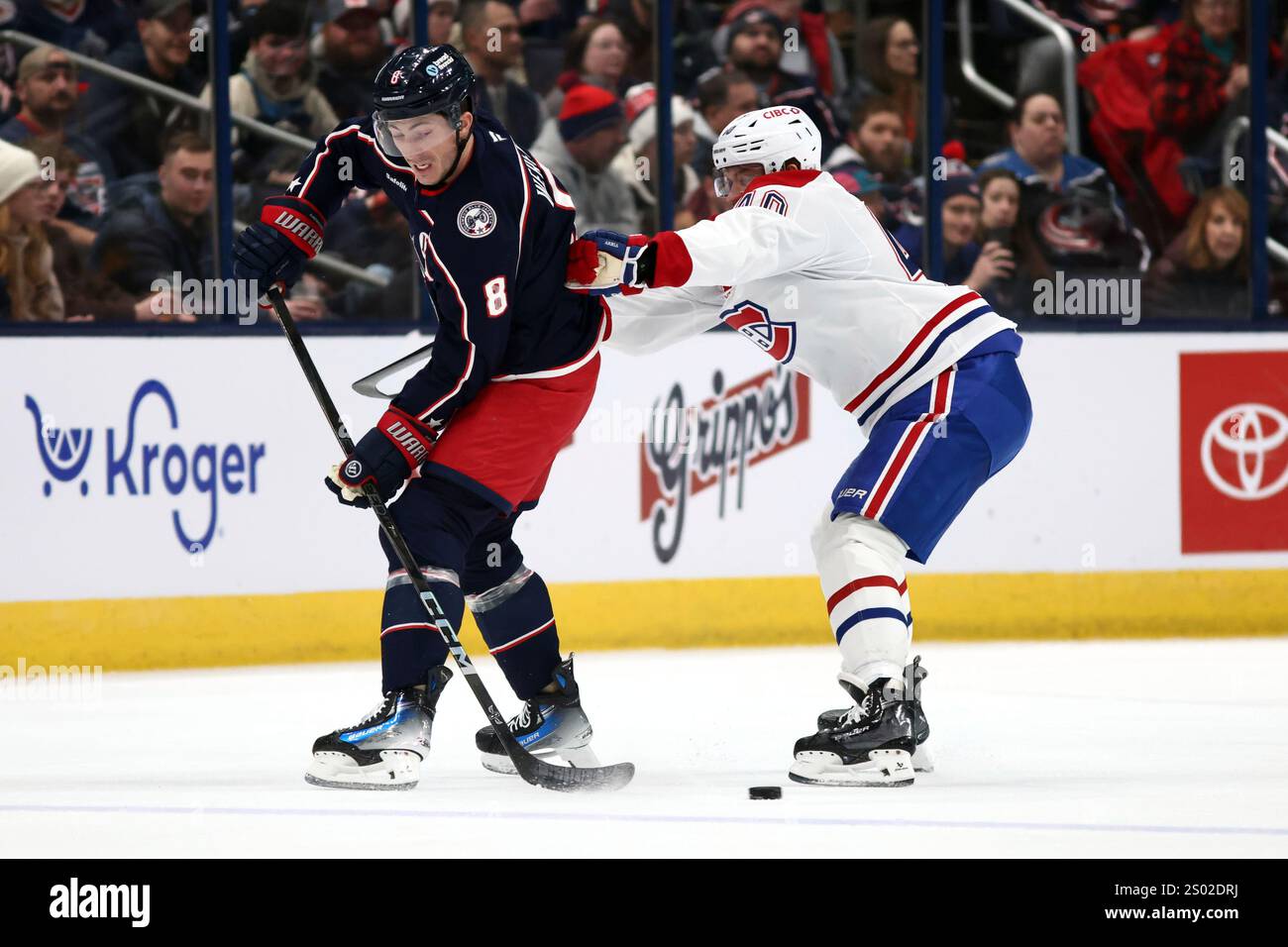 Columbus Blue Jackets defenseman Zach Werenski, left, passes the puck ...