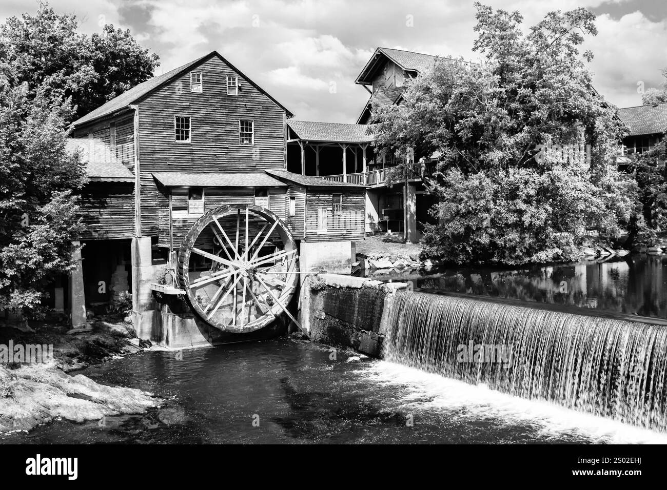 A black and white photo of a mill with a water wheel and a waterfall ...