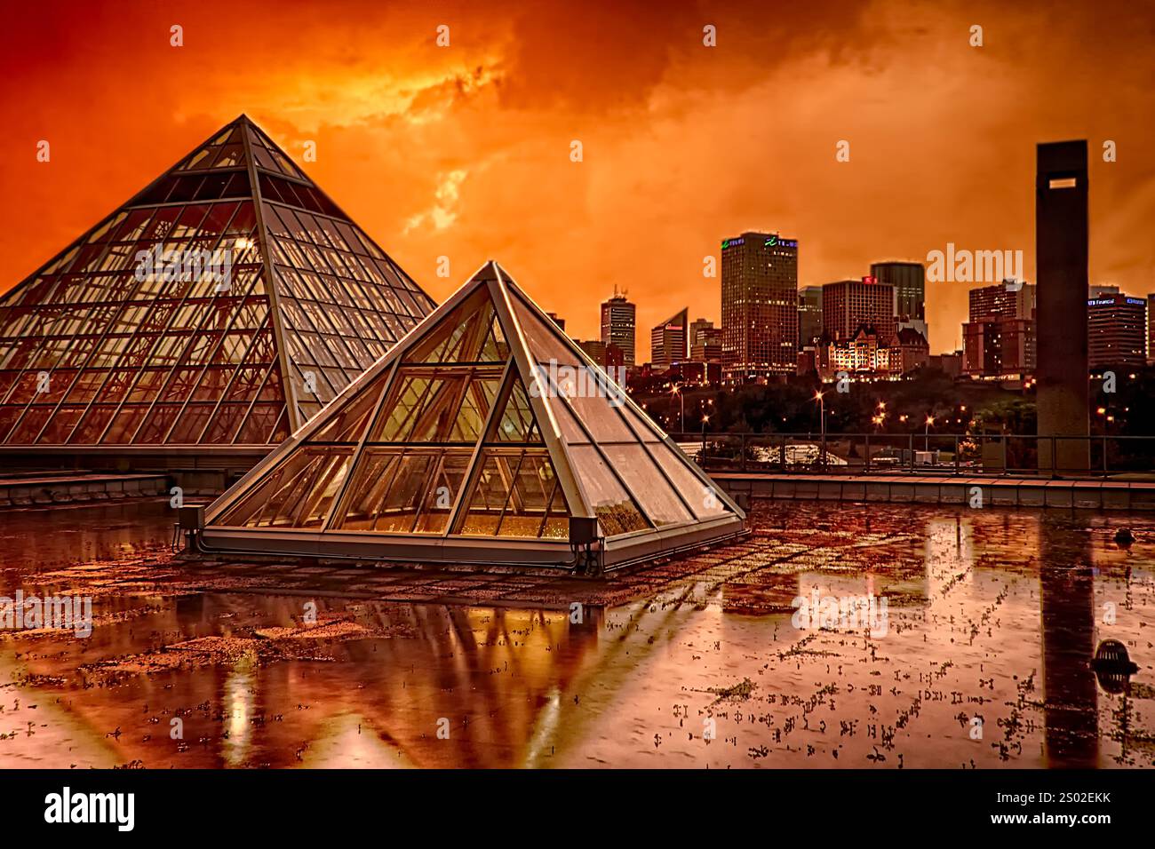 A city skyline is reflected in the water below a pyramid. The sky is ...