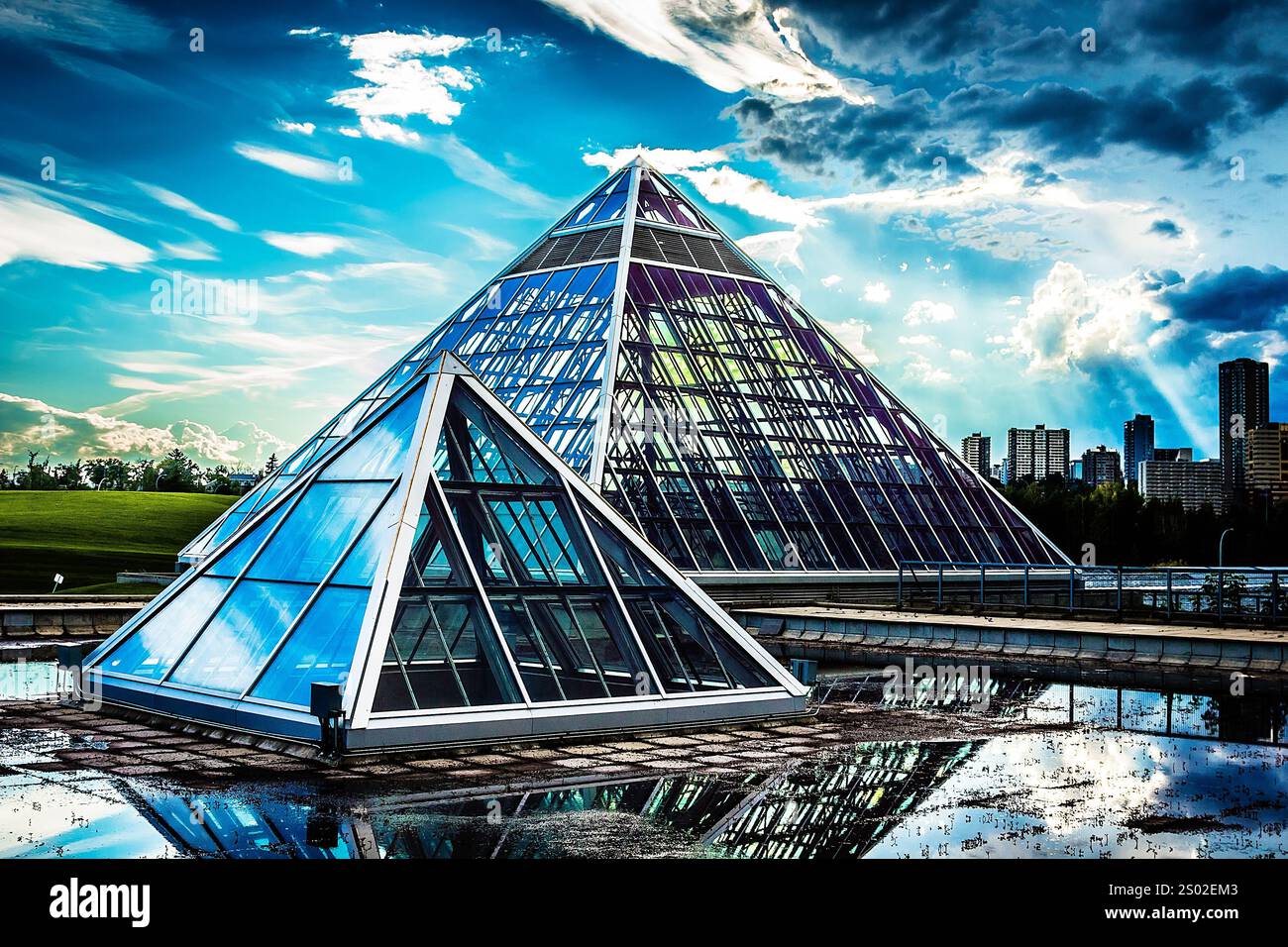 A large pyramid building with a glass roof and a large pool of water in ...