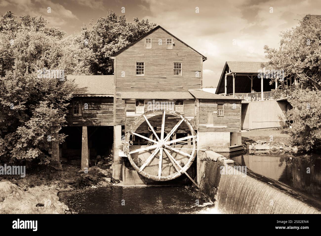 A large wooden building with a water wheel in front of it. The water ...
