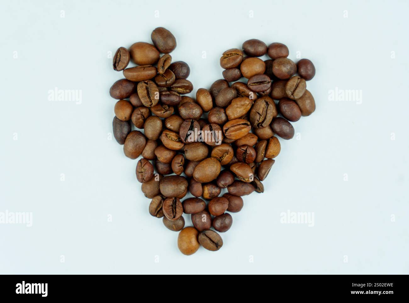 Roasted coffee beans neatly arranged in the shape of a heart on a clean ...