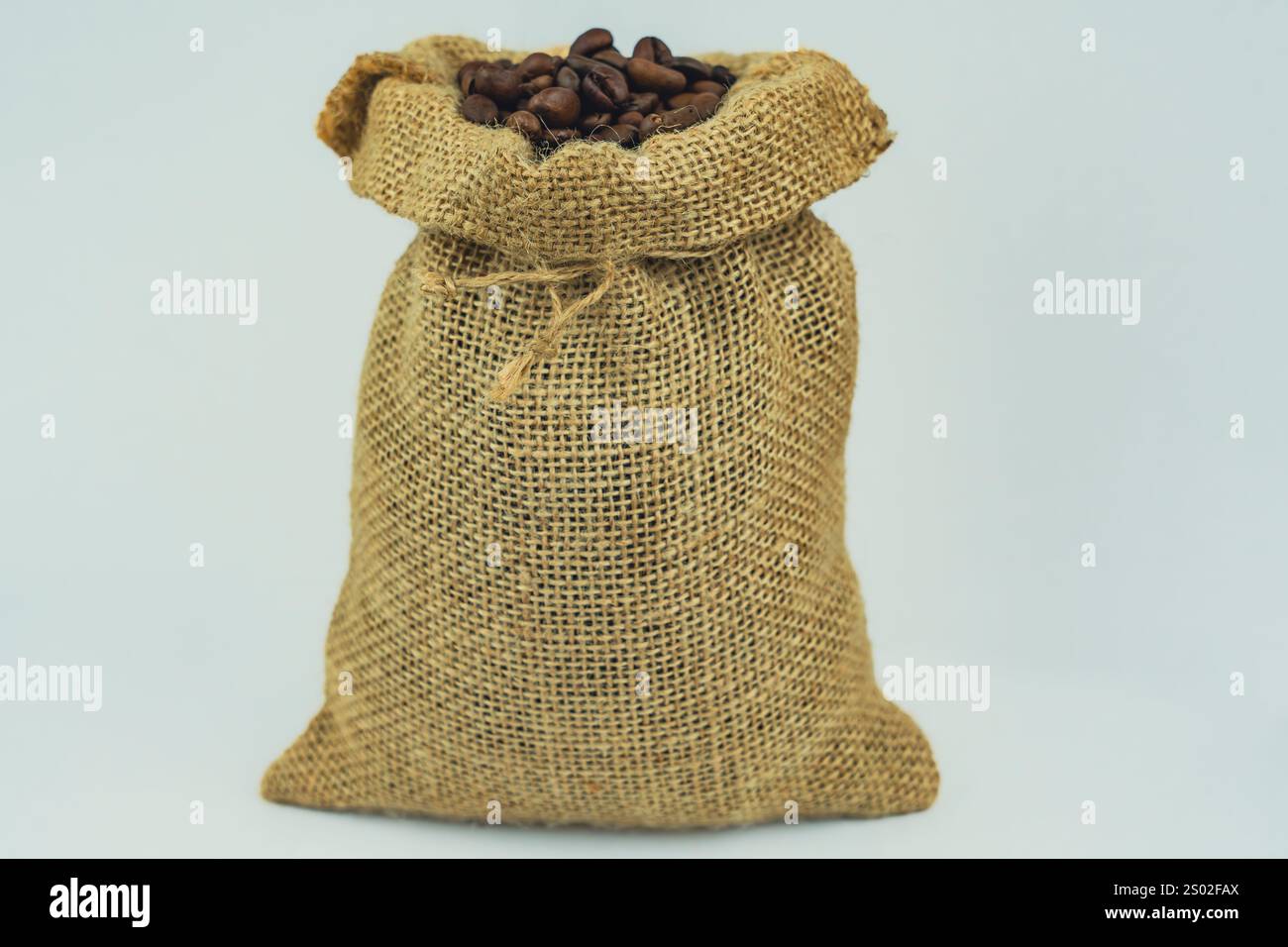 A burlap sack tightly filled with roasted coffee beans, standing ...