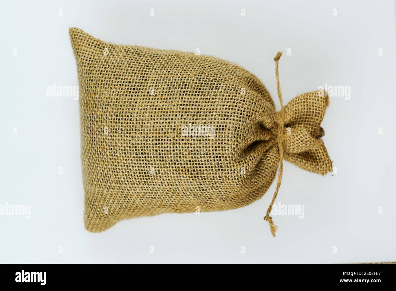 A rustic burlap sack tied with twine placed on a clean white background ...
