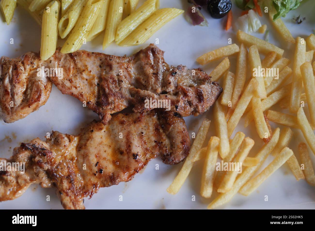 Grilled chicken with pasta and crispy fries makes a satisfying meal ...