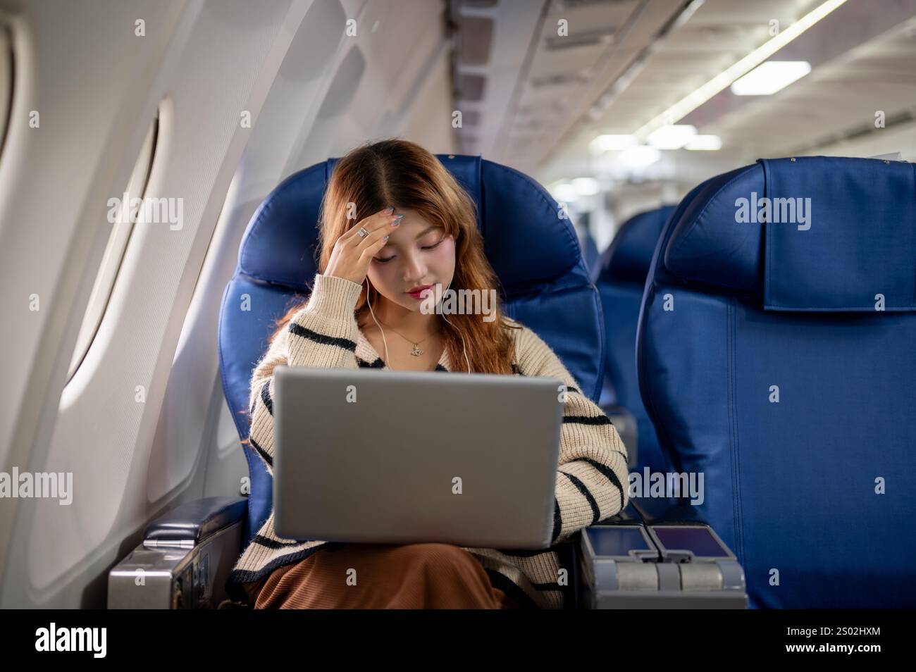 A tired Asian woman in cozy clothes feels dizzy or airsick while ...