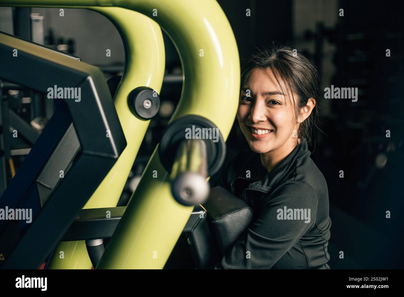 Portrait of beautiful Asian young woman performing squats on a gym ...