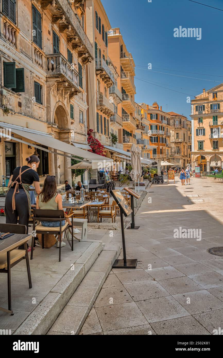 A bustling café-lined street filled with people enjoying the sunny ...