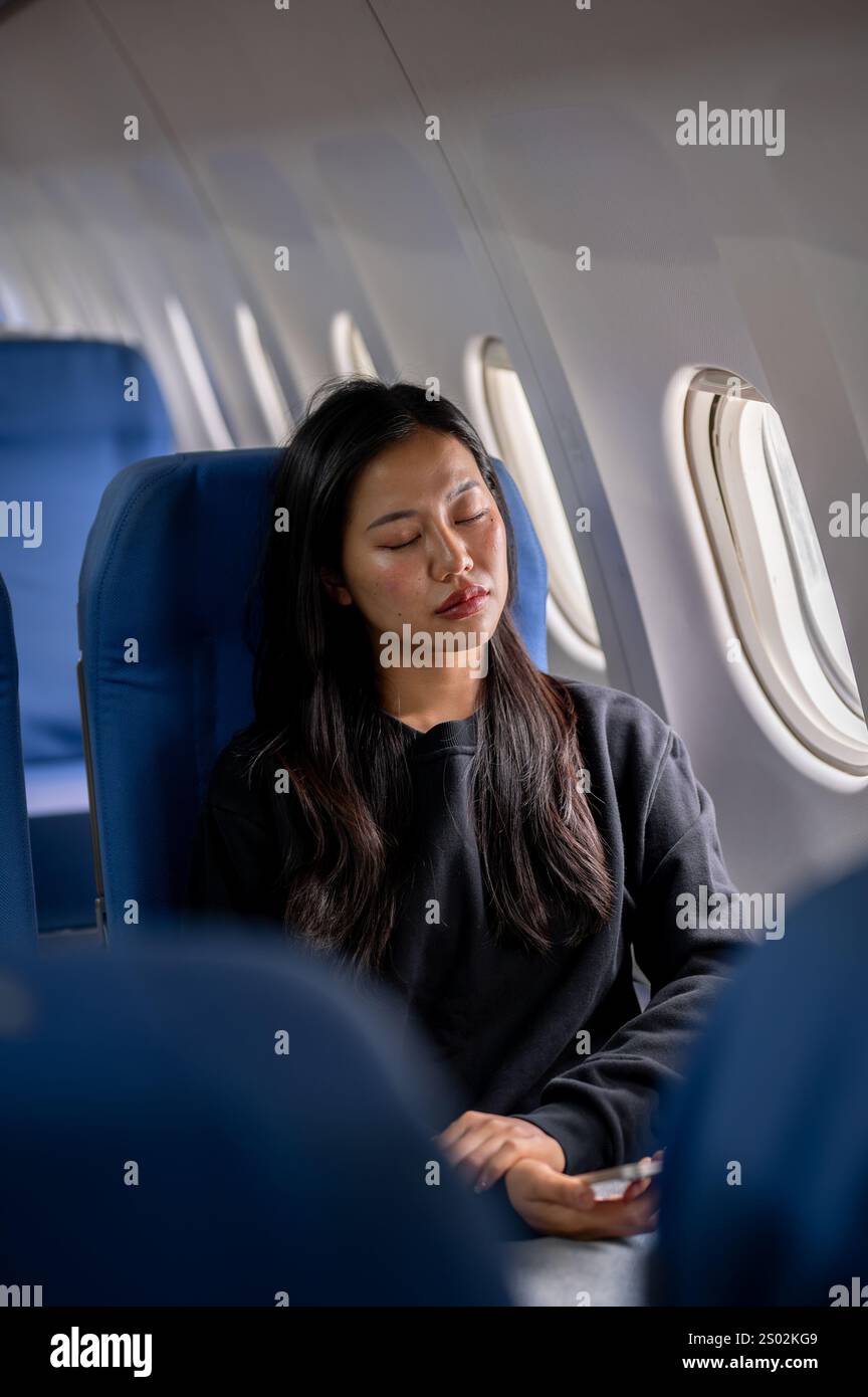 A relaxed and calm Asian female passenger falls asleep during the ...