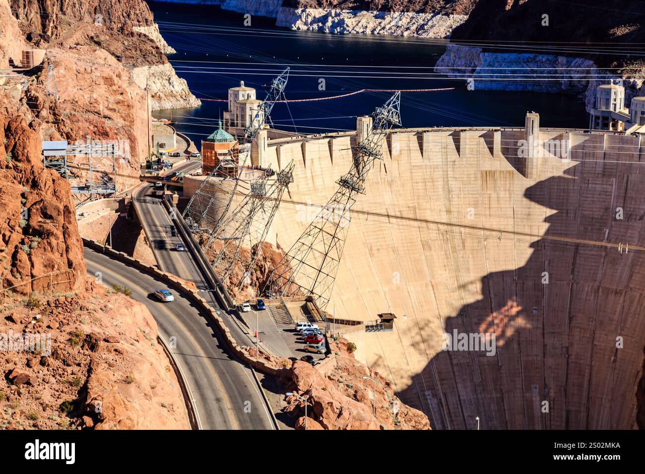 A large dam is seen in the distance with a road running through it. The ...