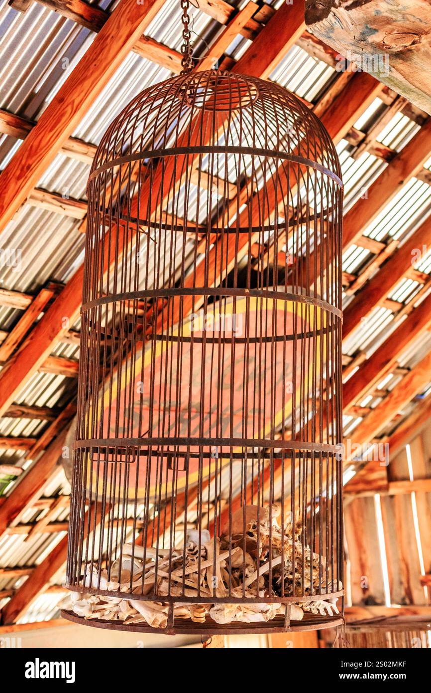 A cage with a yellow and red sign hanging from it. The cage is made of ...