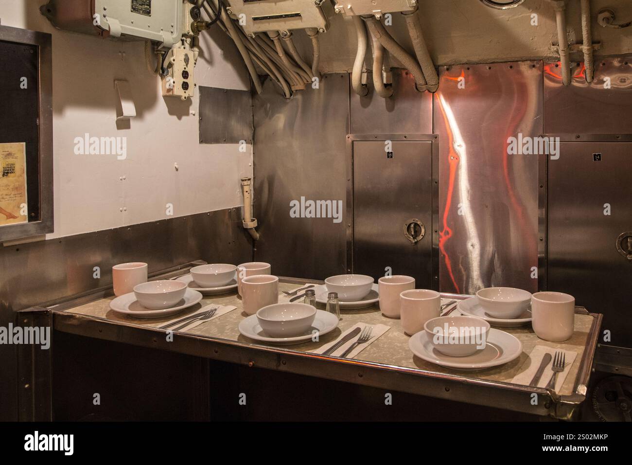 A table with plates and silverware is set up in a kitchen. The table is ...