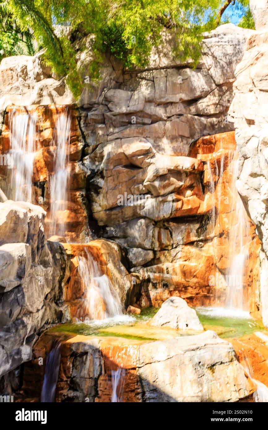 A waterfall with a yellowish brown color. The water is flowing down the ...