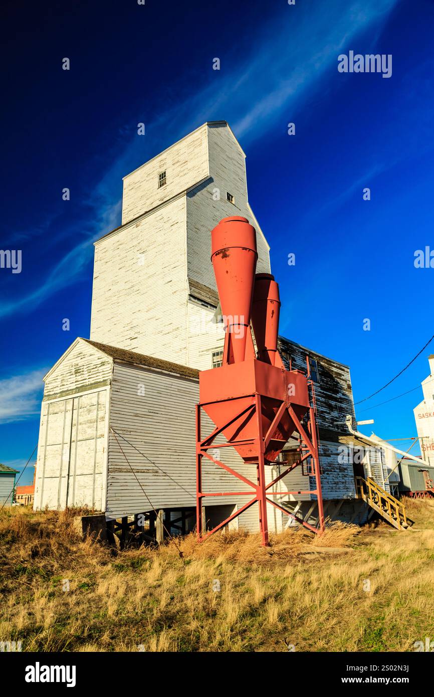 A large red silo stands next to a white building. The silo is tall and ...