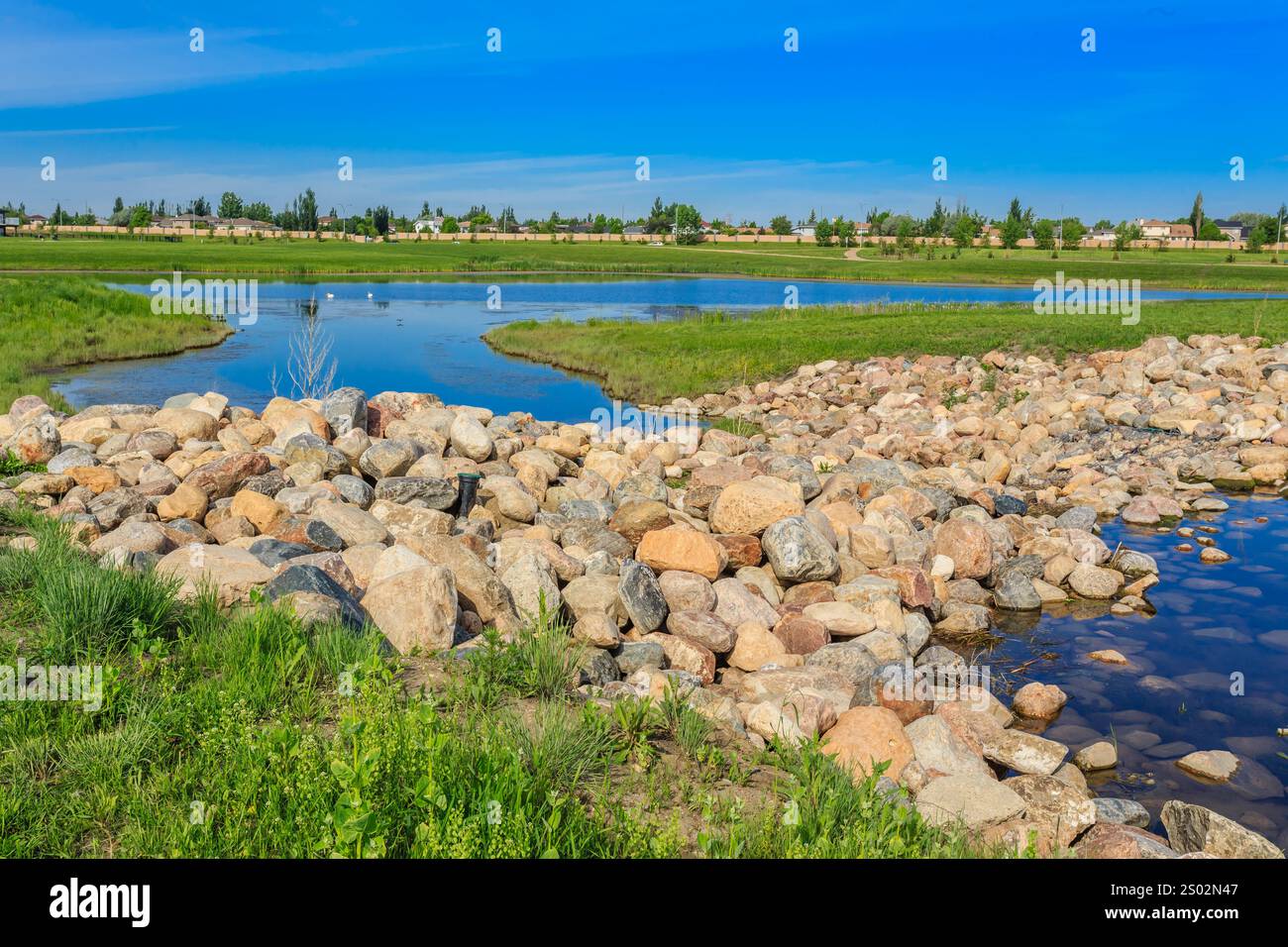 A rocky shoreline with a body of water in the background. The water is ...