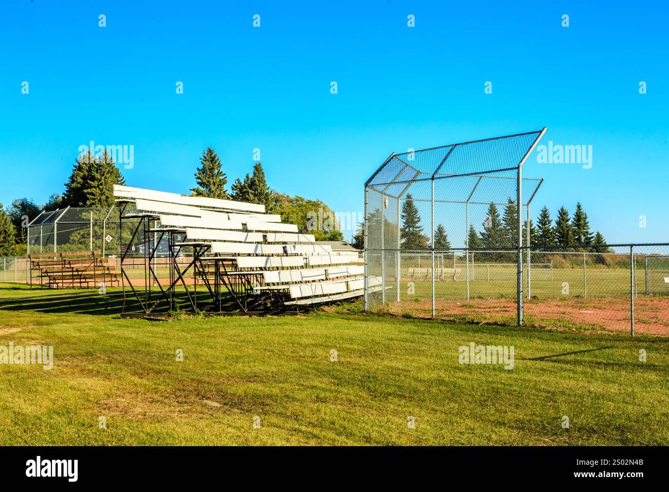 A baseball field with a fence and bleachers. The bleachers are empty ...