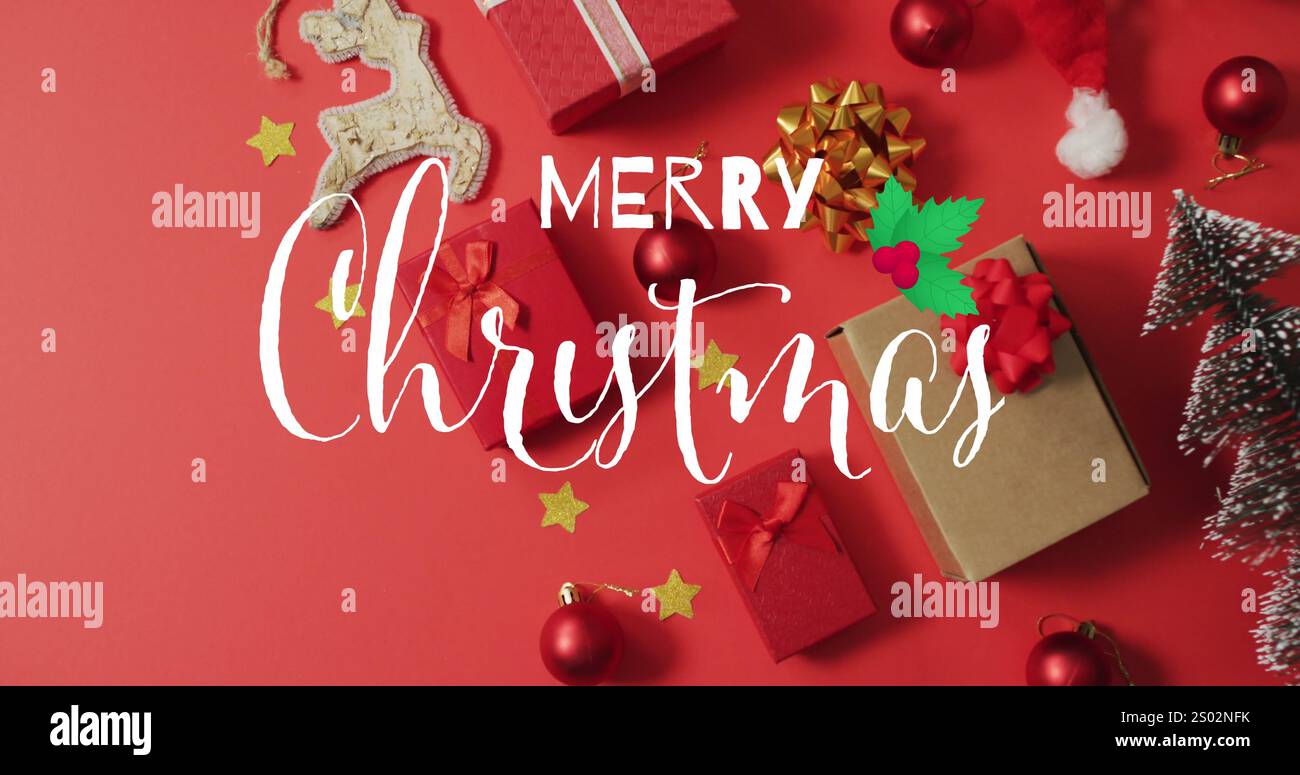 Image of merry christmas over presents and decorations on red surface ...