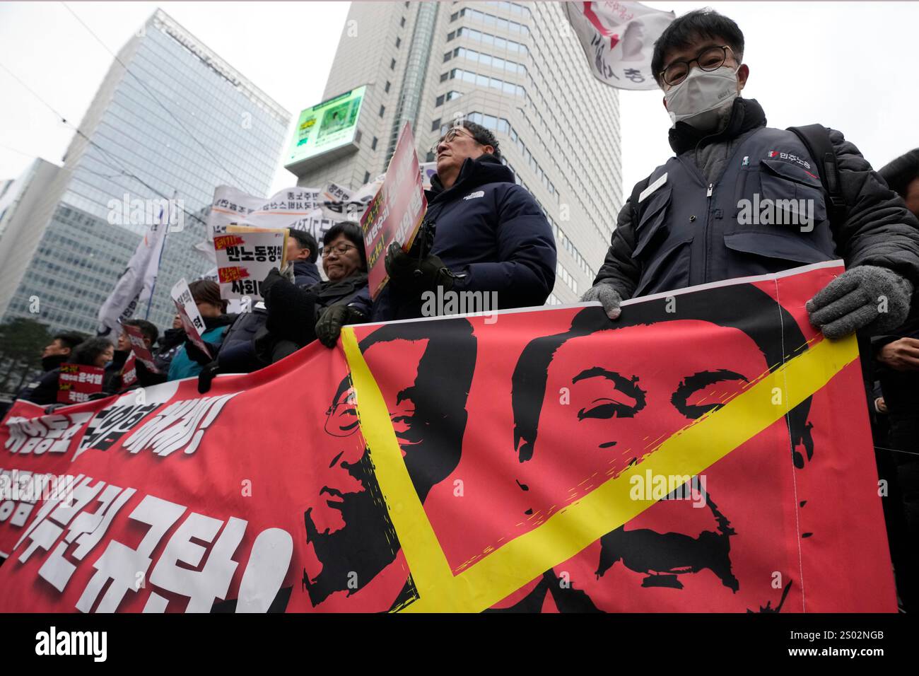 Protesters hold a banner showing images of impeached President Yoon Suk ...