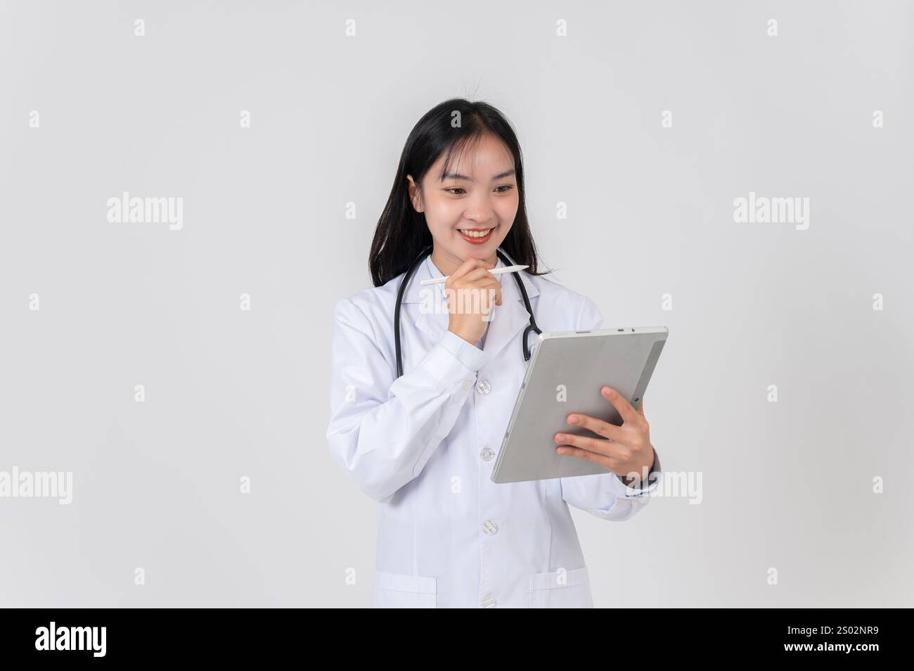 A beautiful, positive Asian female doctor in a white gown stands ...