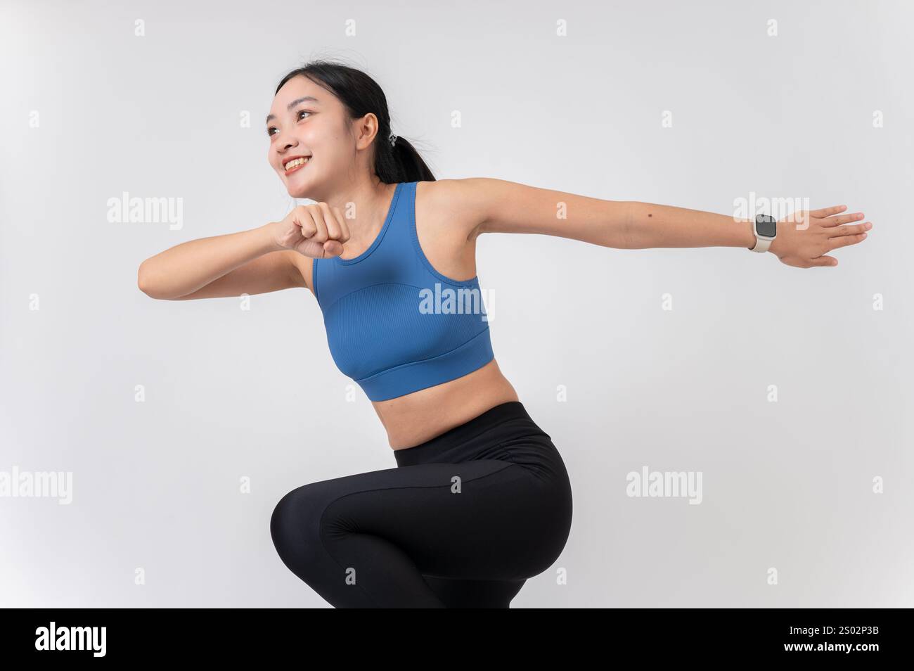 A sporty, confident Asian woman in sportswear jumping with her knee ...