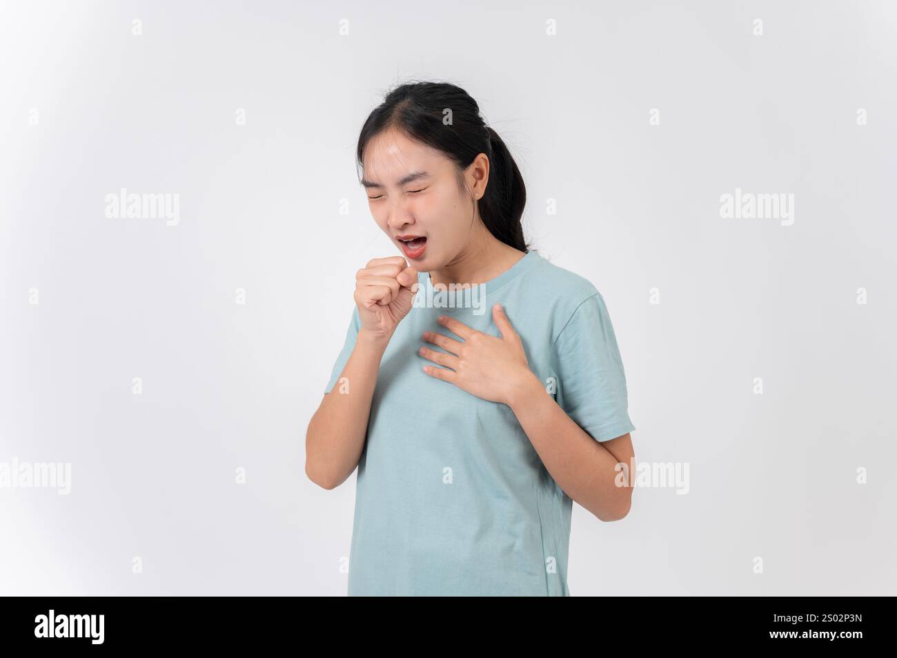 A sick, uncomfortable young Asian woman coughing, suffering from a sore ...