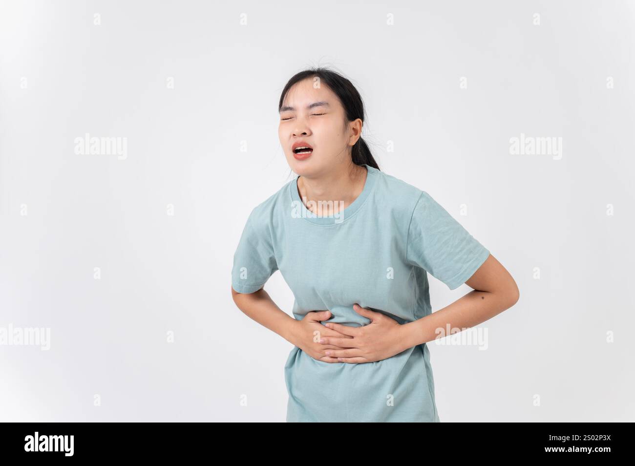 A sick, uncomfortable young Asian woman touching her stomach, suffering ...