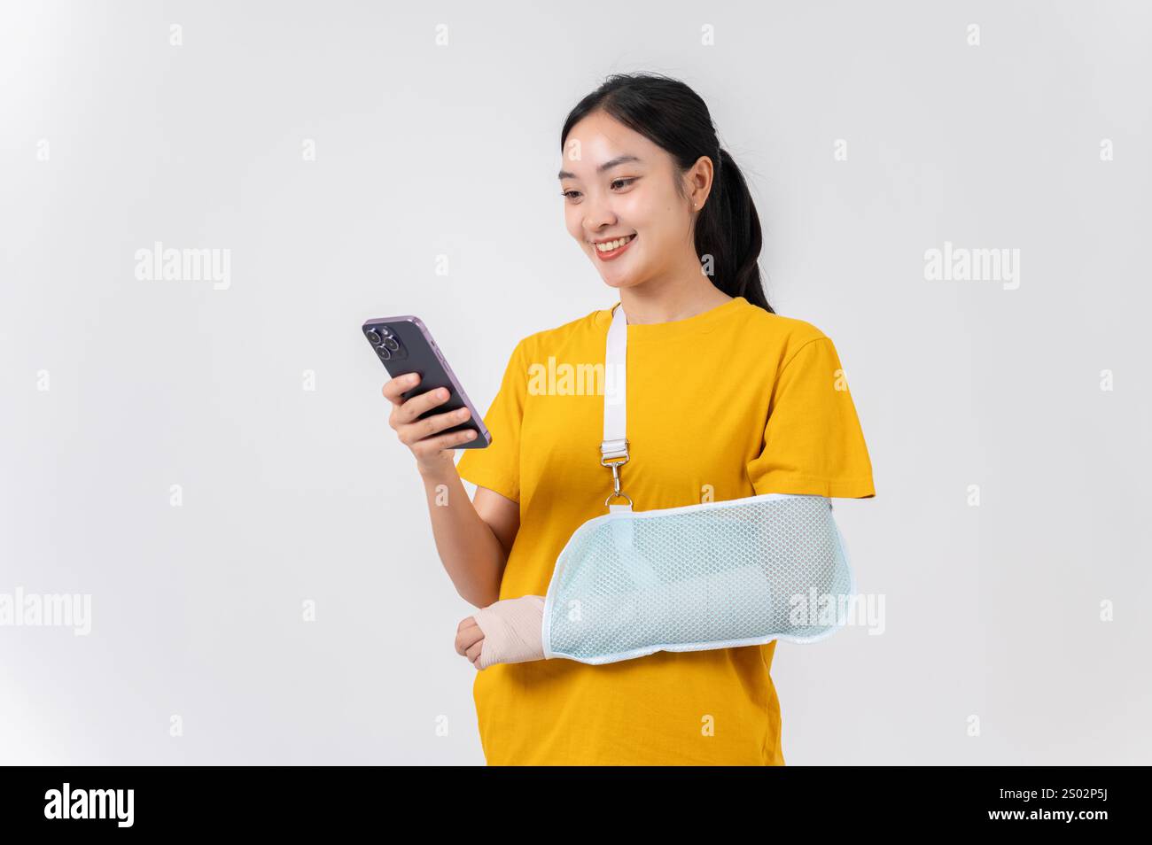 A smiling, carefree Asian woman with her broken arm, wrapped in a ...