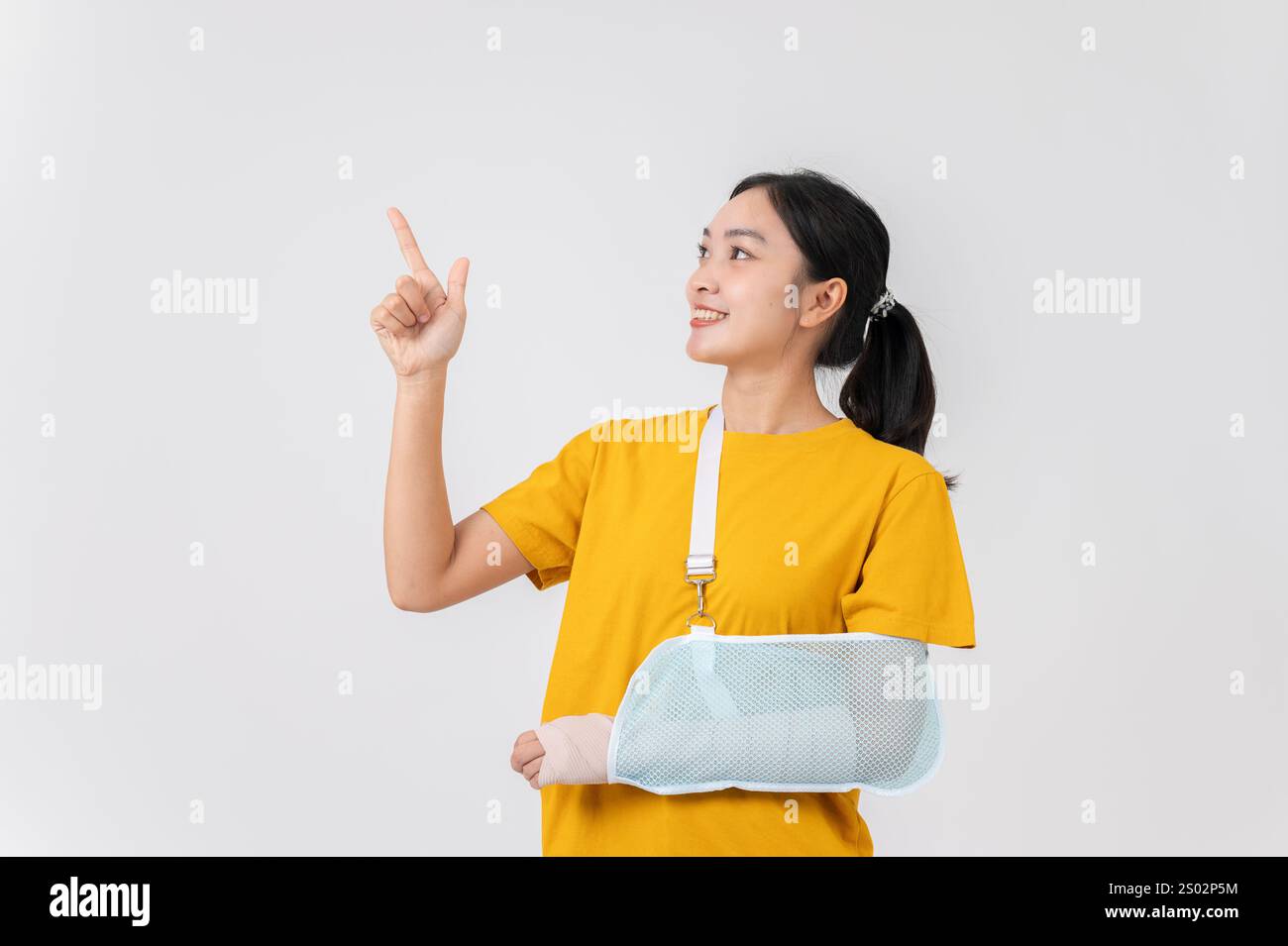 A smiling Asian woman with her broken arm, wrapped in a plaster bandage ...
