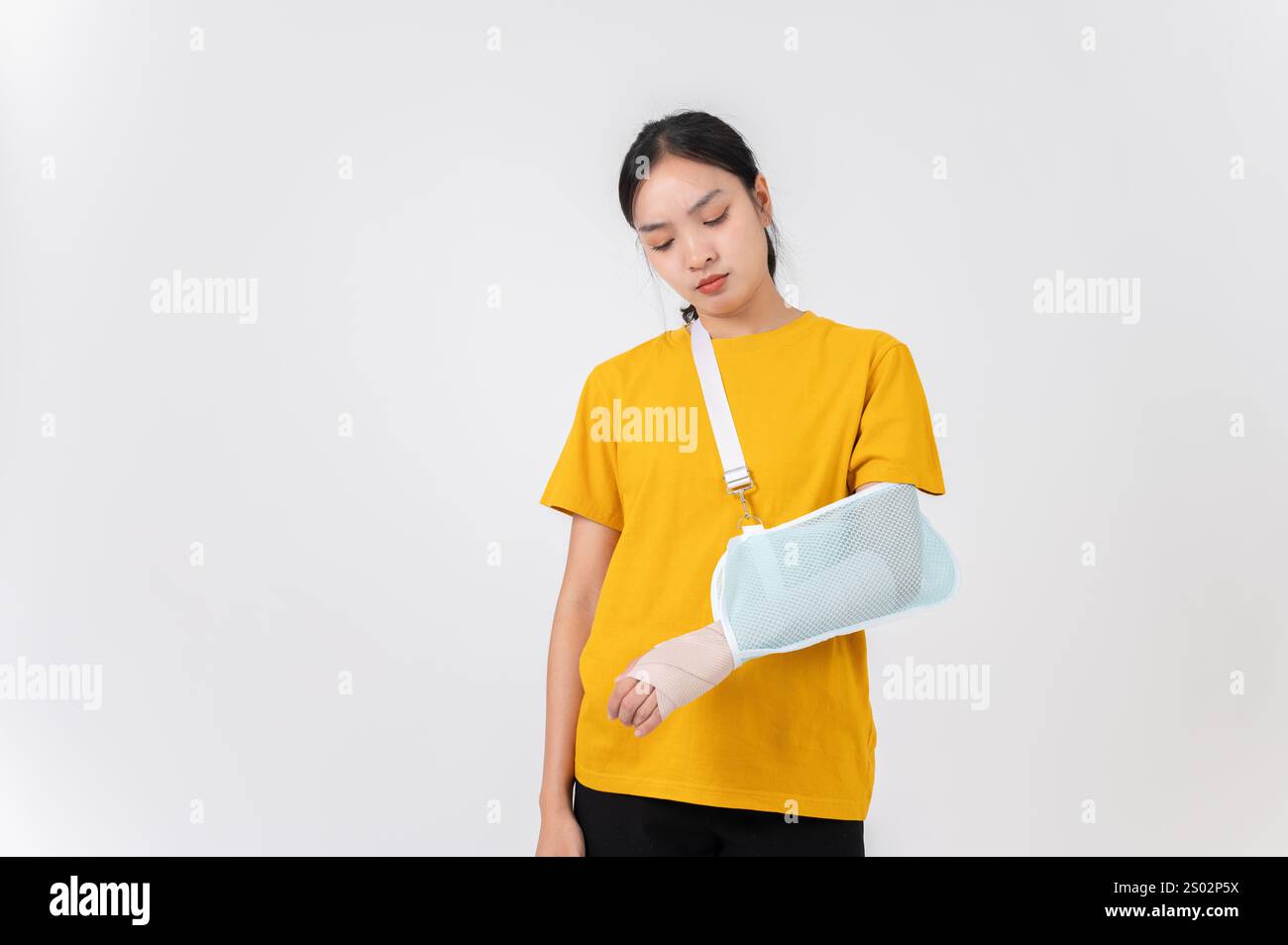 A sad Asian woman with a broken arm wrapped in a plaster bandage ...