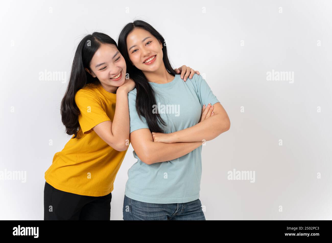 Two lovely, smiling young Asian women in casual clothes hugging while ...