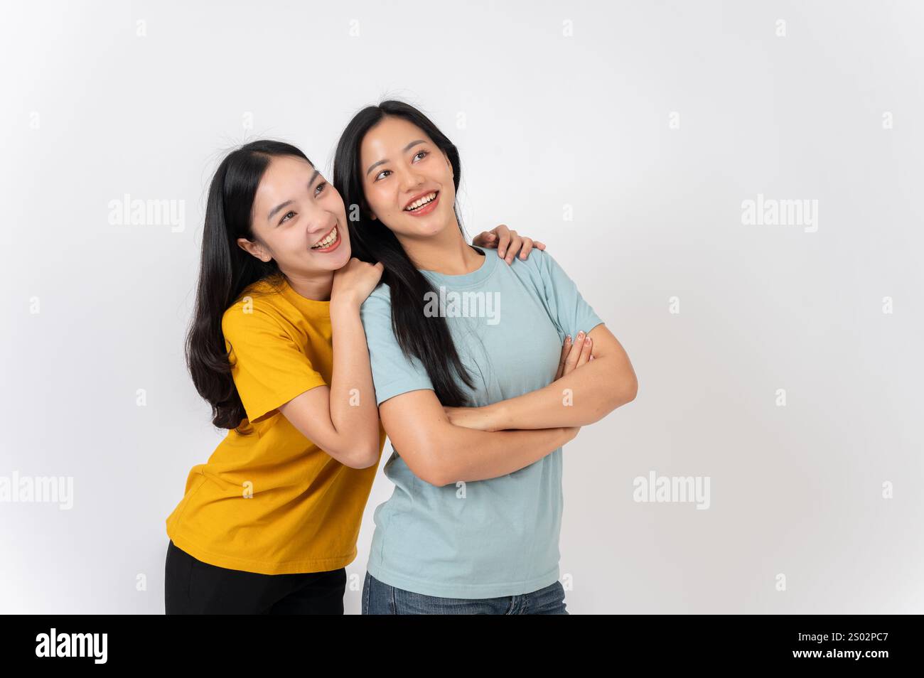 Two lovely, smiling young Asian women in casual clothes hugging while ...