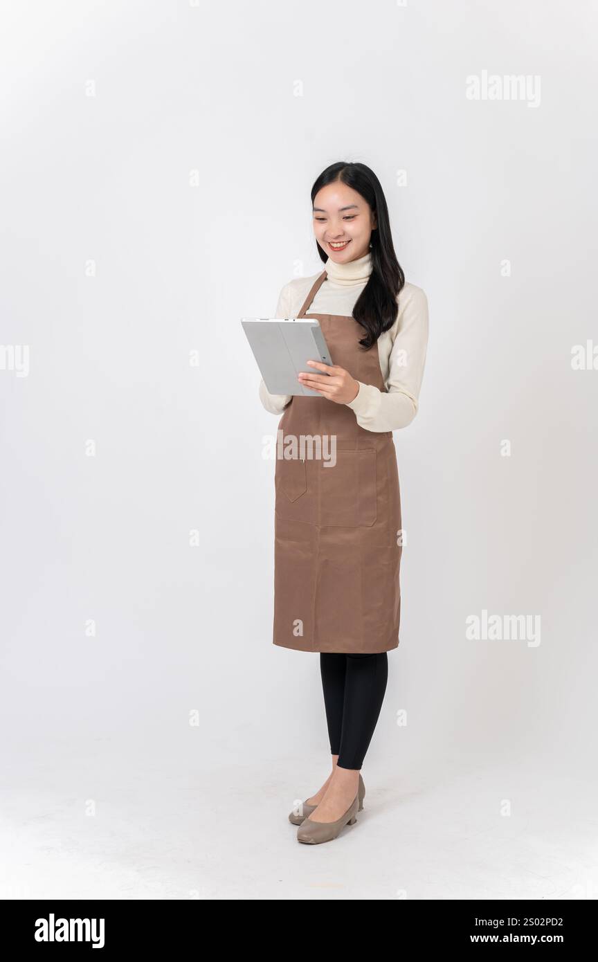 A beautiful Asian female waitress or coffee shop staff in a brown apron ...