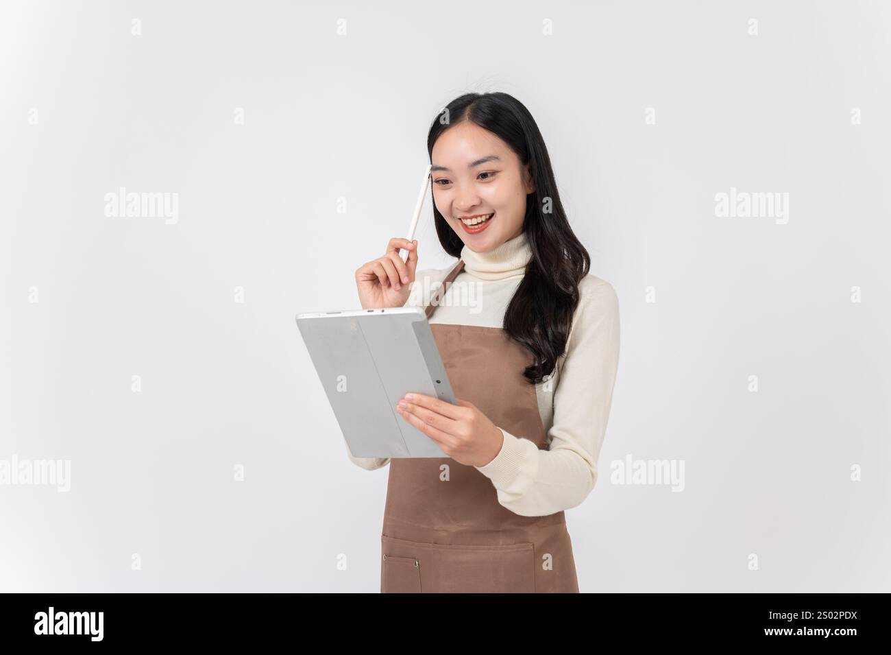 A smiling Asian female waitress or coffee shop staff in a brown apron ...