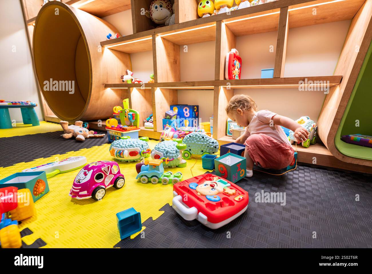 Child exploring toys in a modern playroom. Concept of interactive play ...