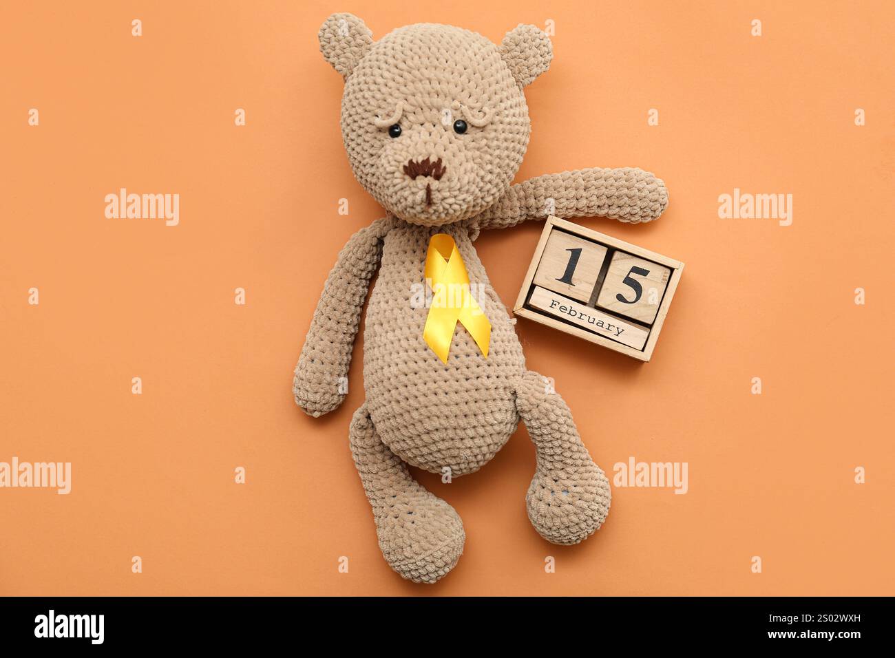 Knitted teddy bear with golden awareness ribbon and calendar with date ...