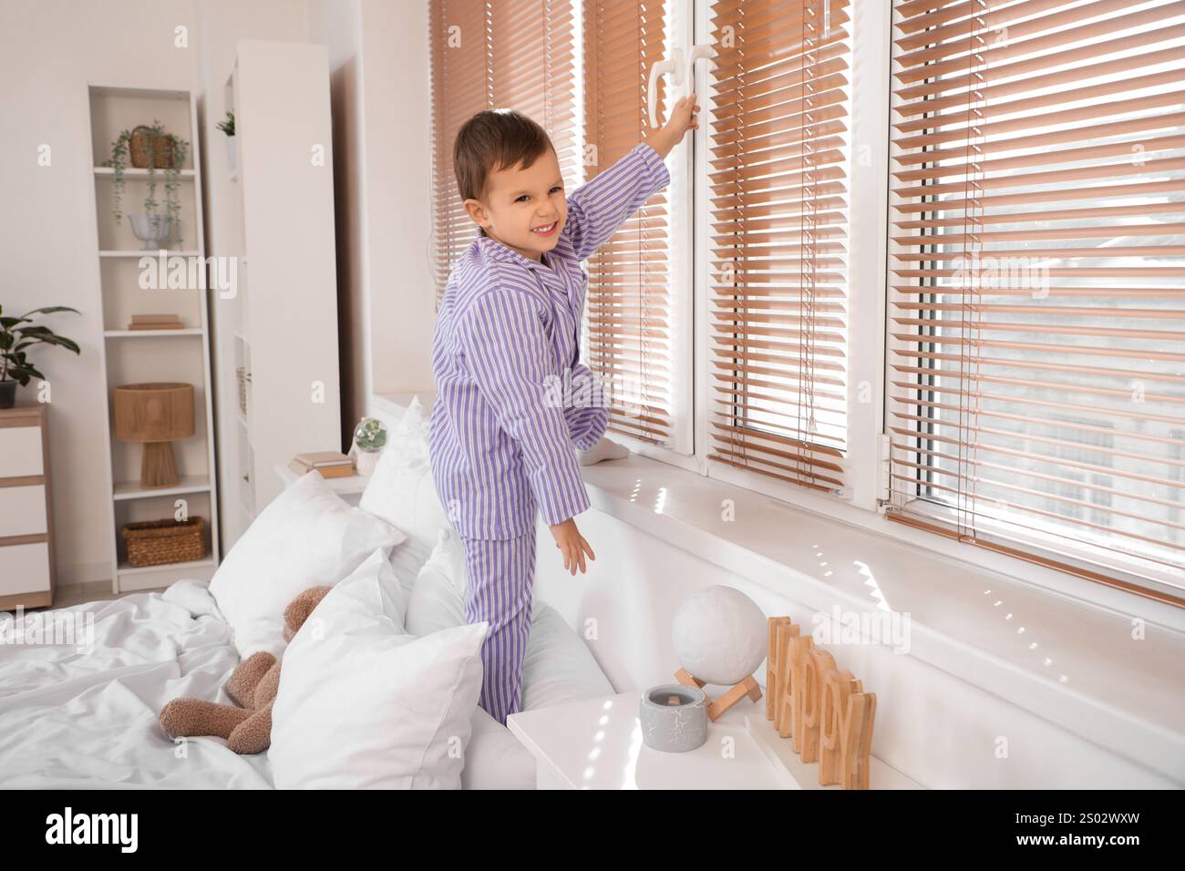 Cute little boy trying to open window in bedroom. Child at risk Stock ...