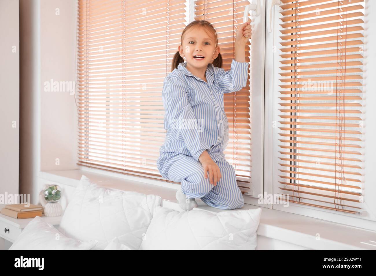 Cute little girl opening window in bedroom. Child at risk Stock Photo ...