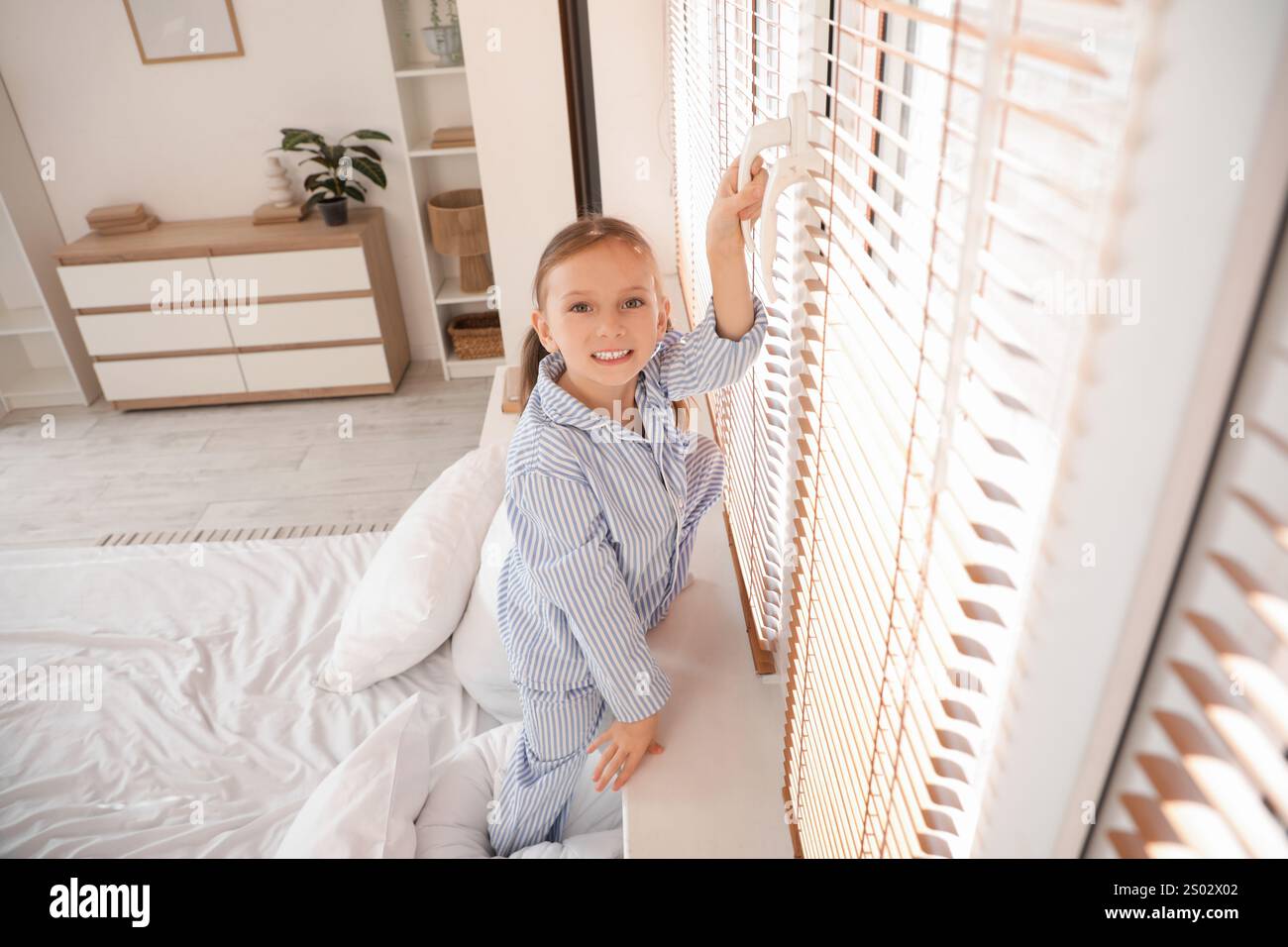 Cute little girl trying to open window in bedroom. Child at risk Stock ...