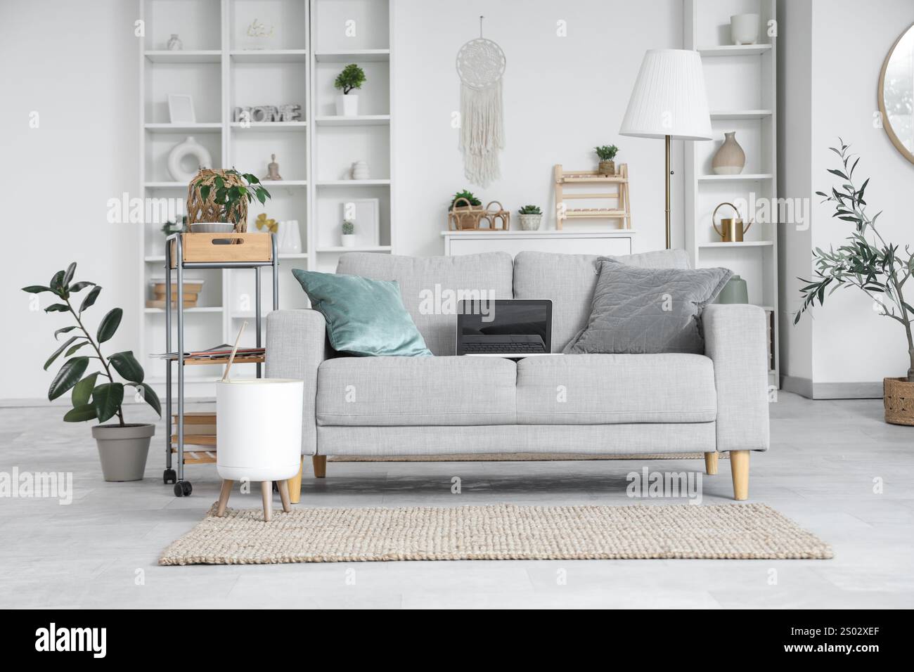 Interior of light living room with sofa, shelf units and trash bin ...