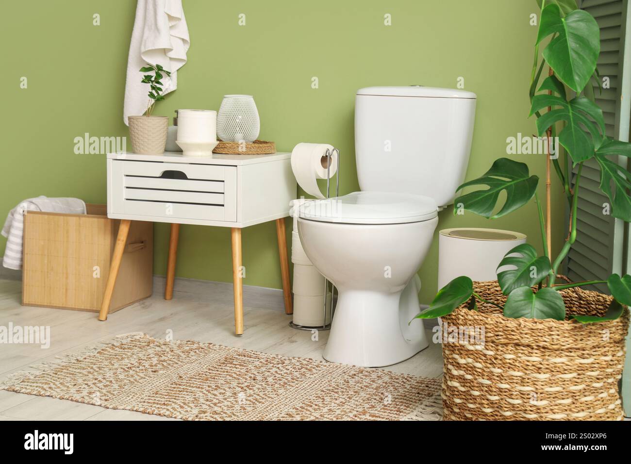 Toilet bowl, bedside table and houseplant in restroom Stock Photo - Alamy