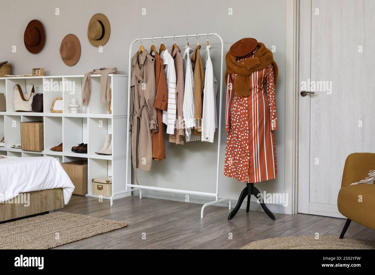Interior of stylish bedroom with clothes rack, shelving unit and ...