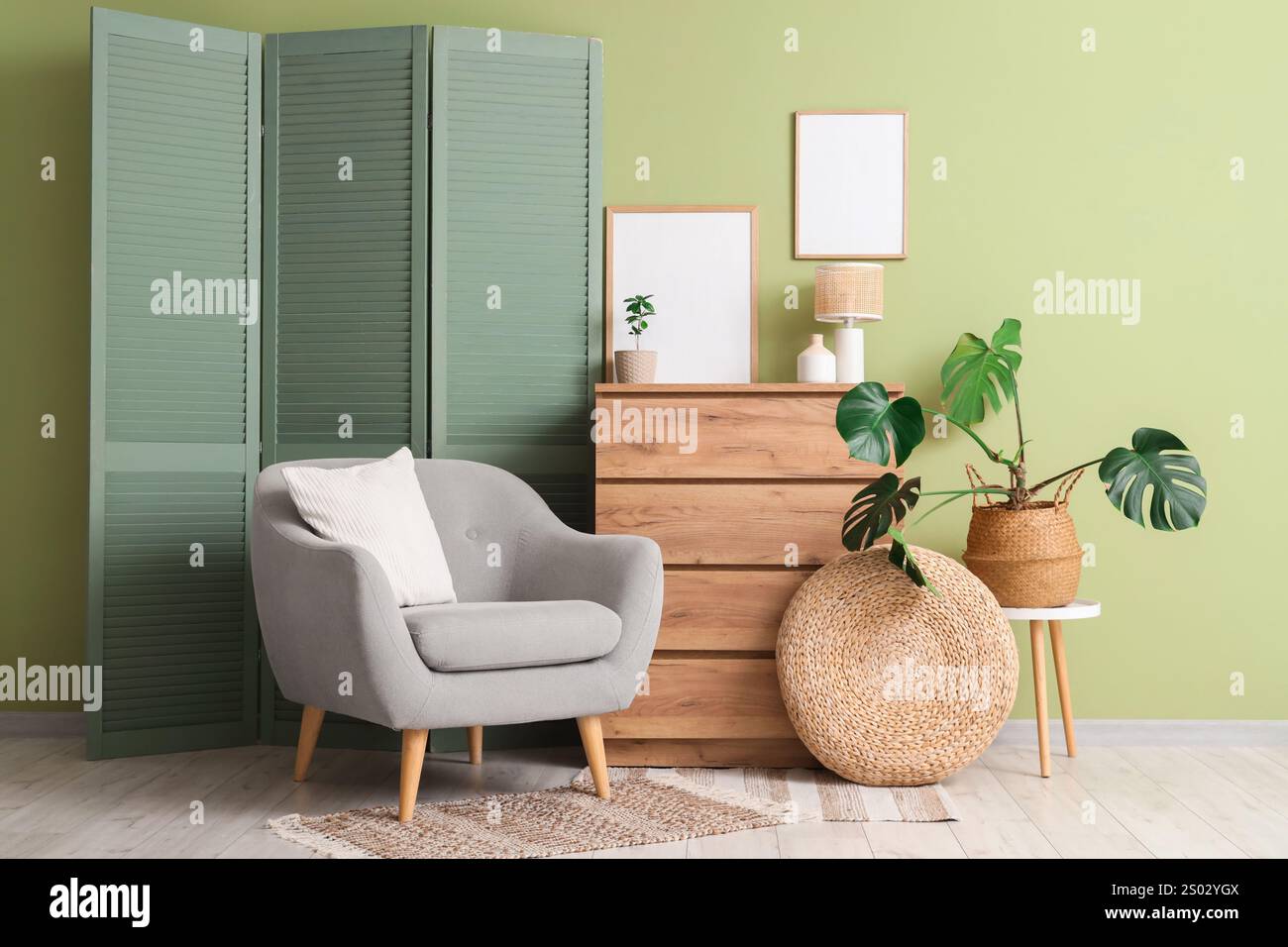 Blank posters on chest of drawers, armchair and folding screen in ...