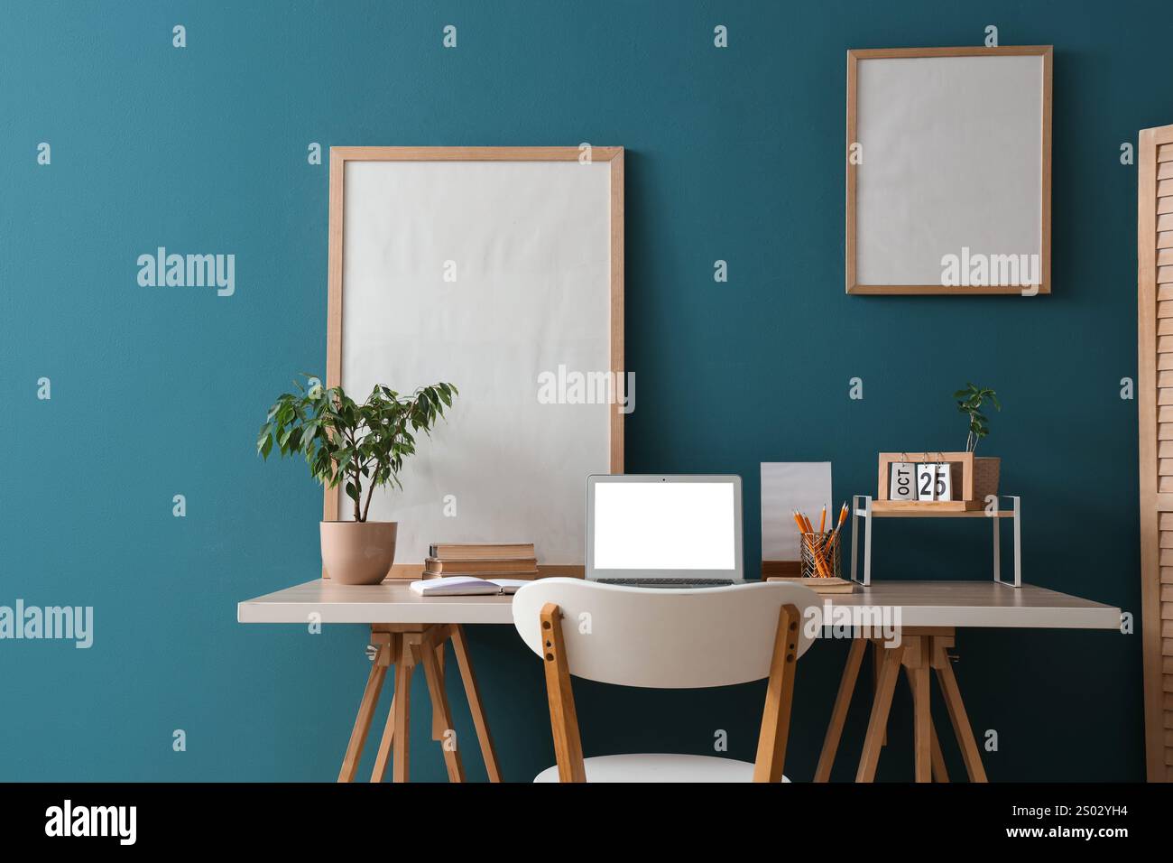 Workplace with laptop and blank posters near blue wall in room Stock ...