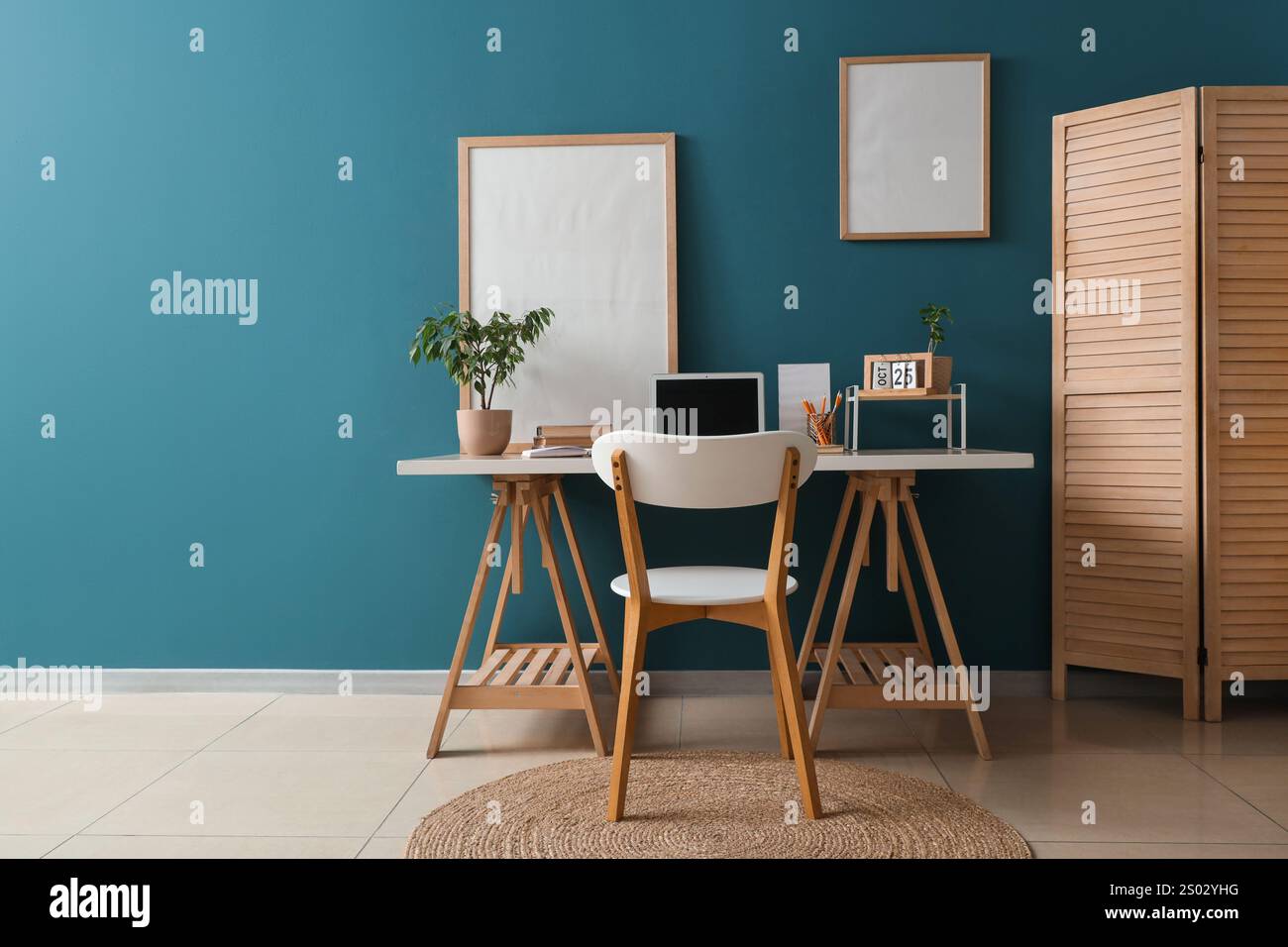 Workplace with laptop and blank posters near blue wall in room Stock ...