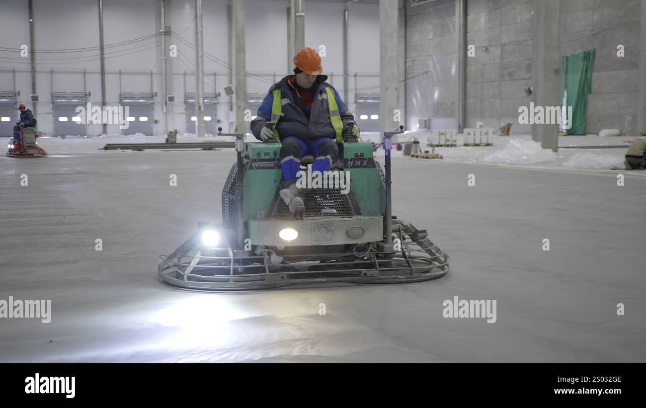 A Worker Who Operates a Concrete Finishing Machine Inside a Warehouse ...