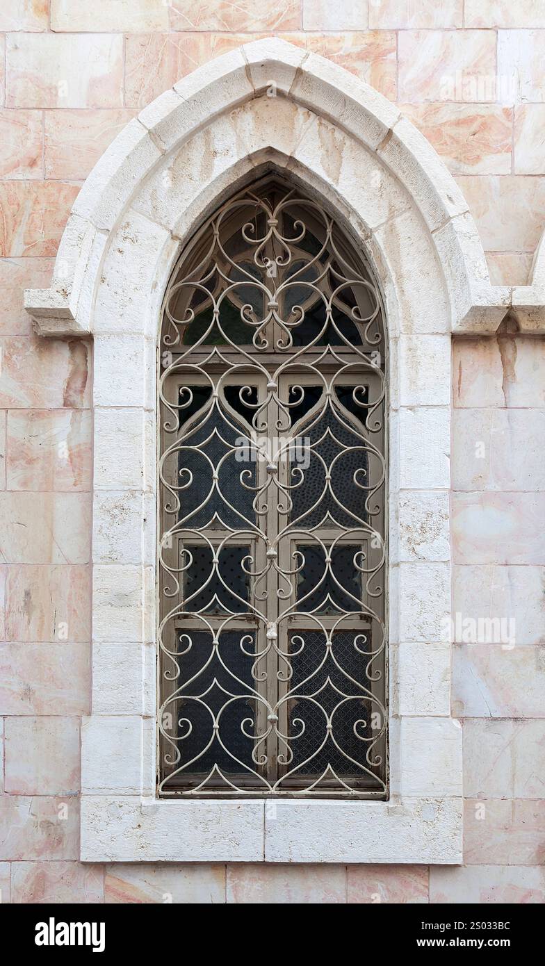 A beautifully crafted gothic window adorns an ancient stone wall ...